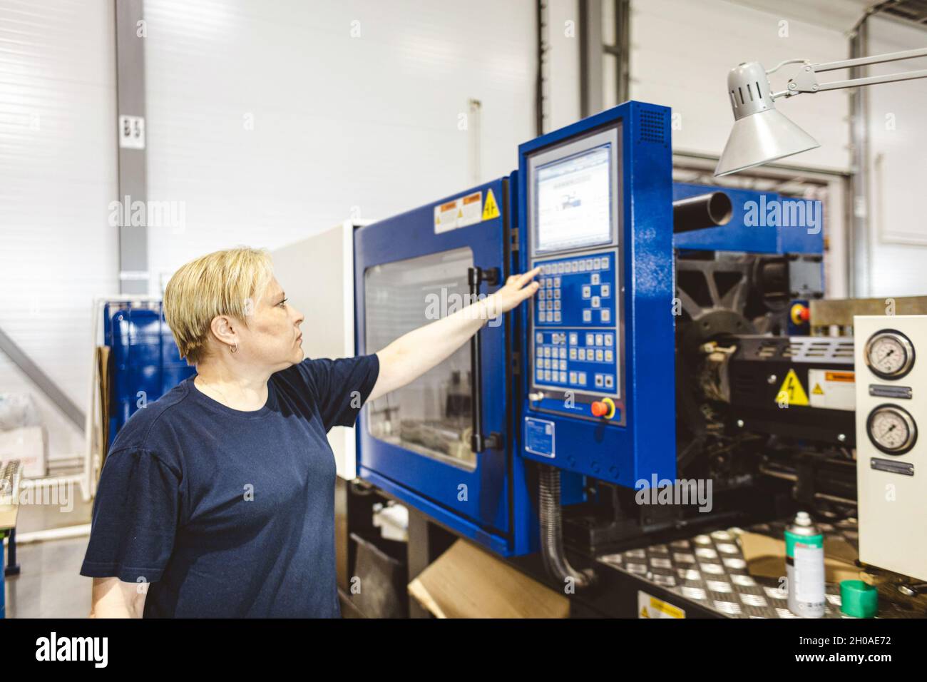 A worker woman presses a button and starts an automatic manufacturing ...