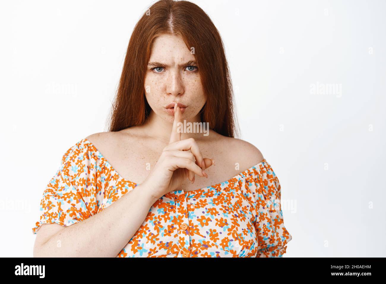 Angry redhead teen girl shh at you, hush with finger pressed to lips ...