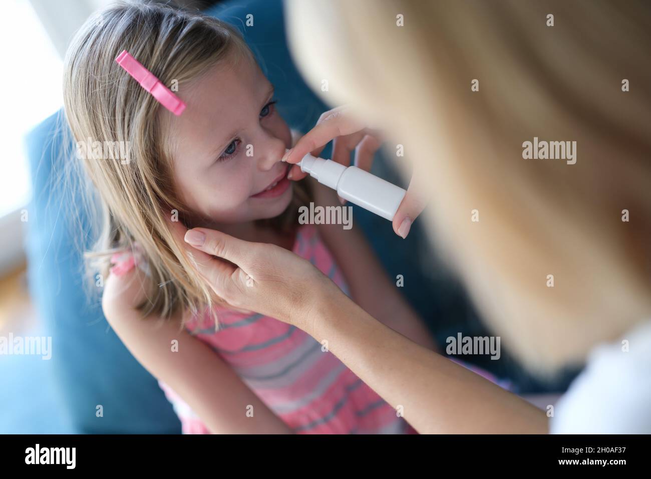 Mother puffing little girl nose with antibacterial drops at home Stock ...