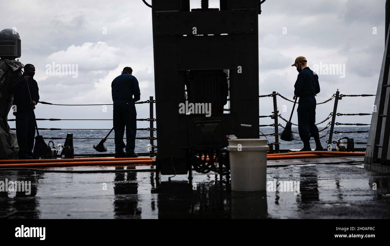 Sailors clean the weather decks during a fresh water washdown aboard ...
