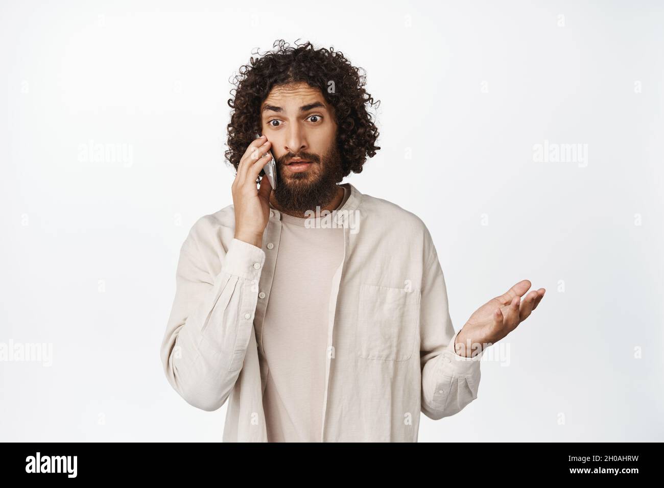 Image of middle eastern man talking on mobile phone, looking confused ...