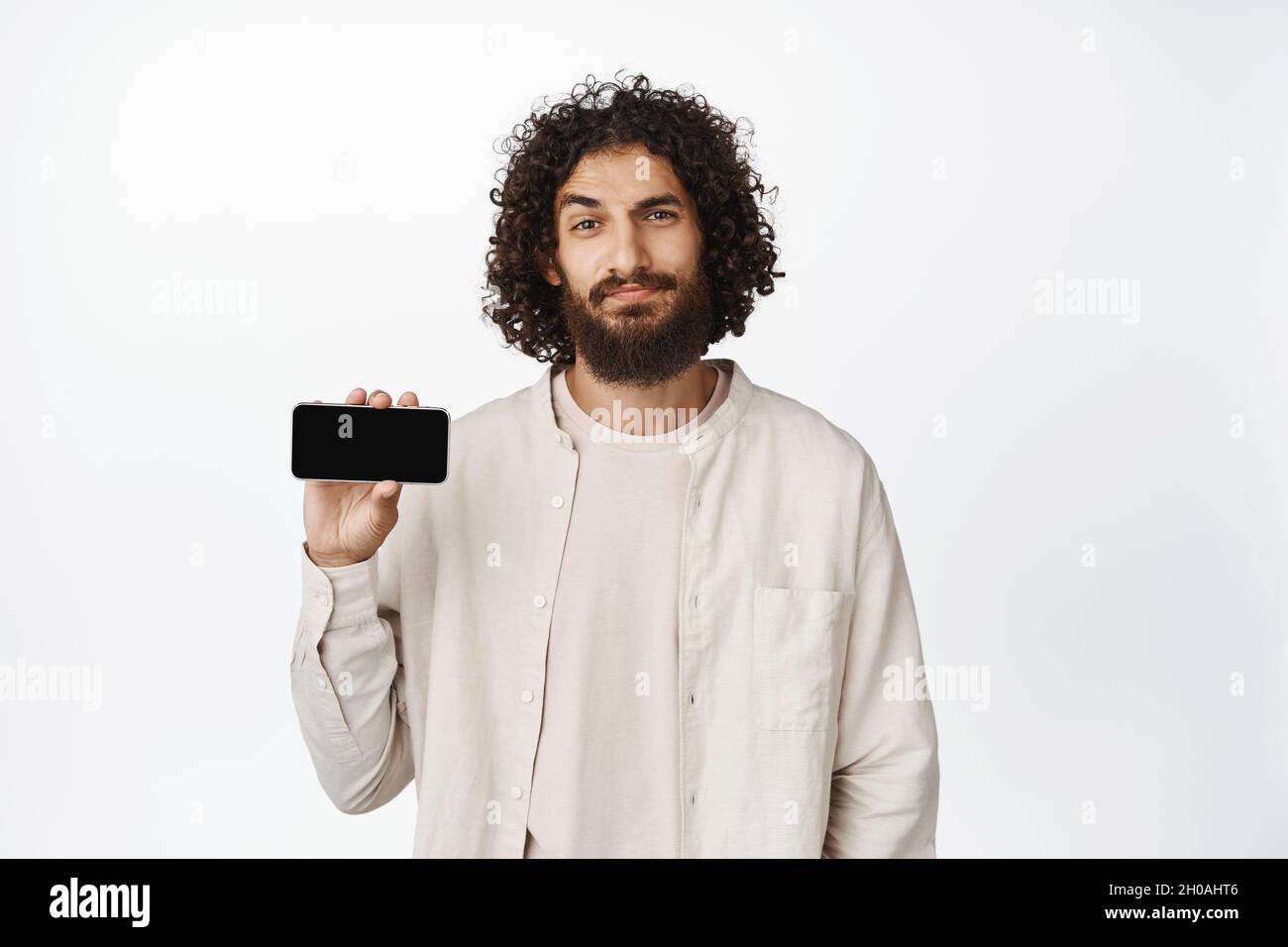 Smiling handsome arab man showing horizontal smartphone screen, app ...
