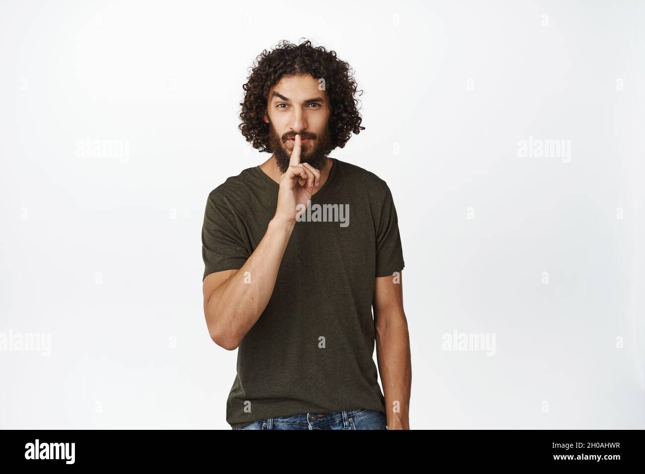 Young middle-eastern guy shushing, making hush sign with finger on lips ...