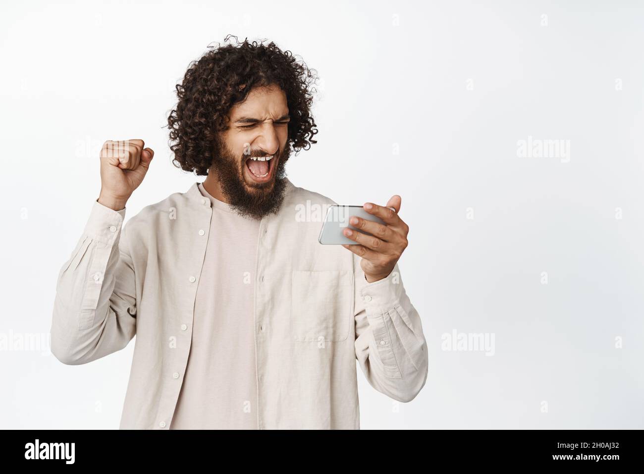 Happy man watching video on smartphone and chanting, using mobile phone ...