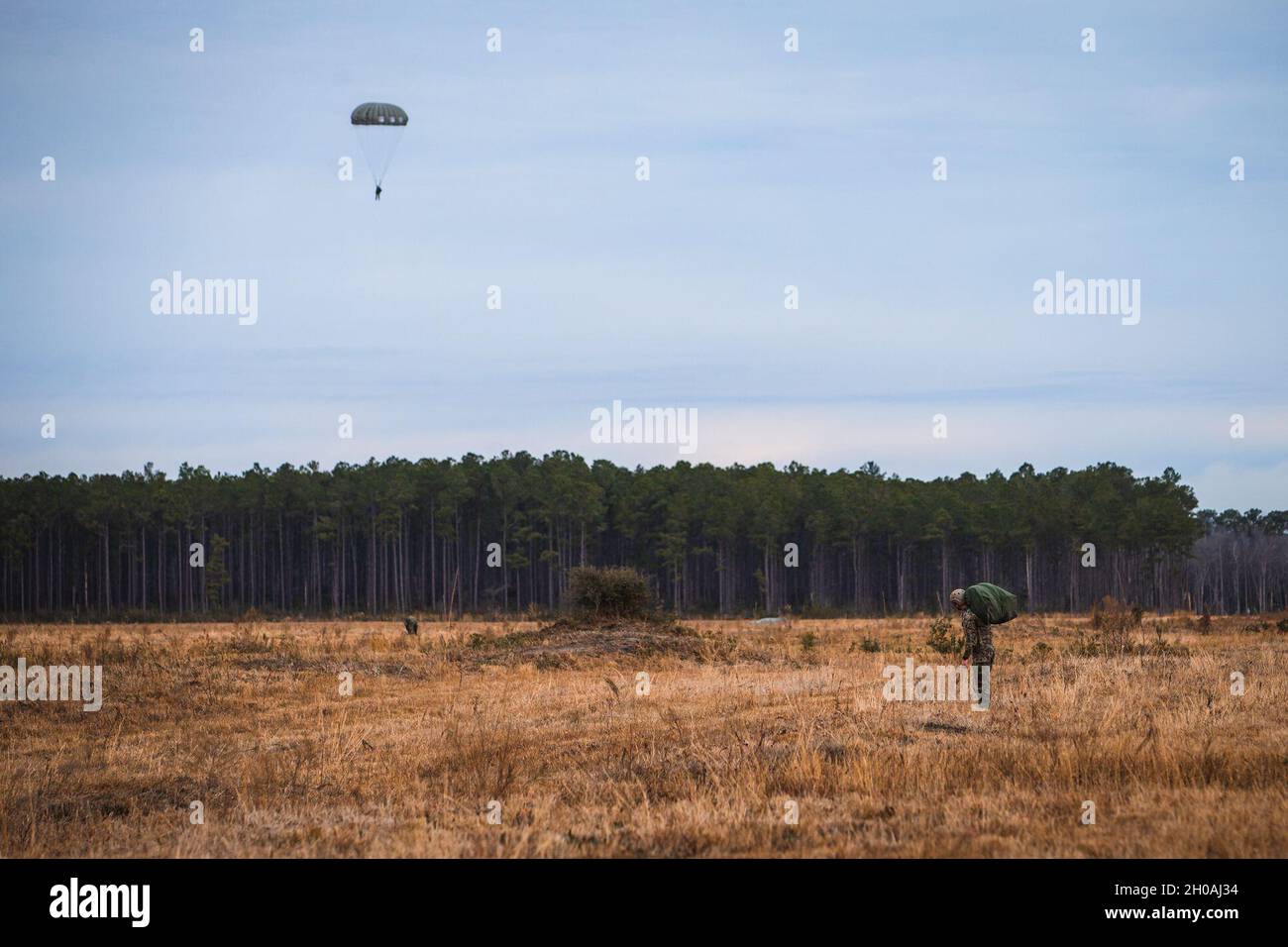 A U.S. Marine holds their repacked parachute over their back as they ...