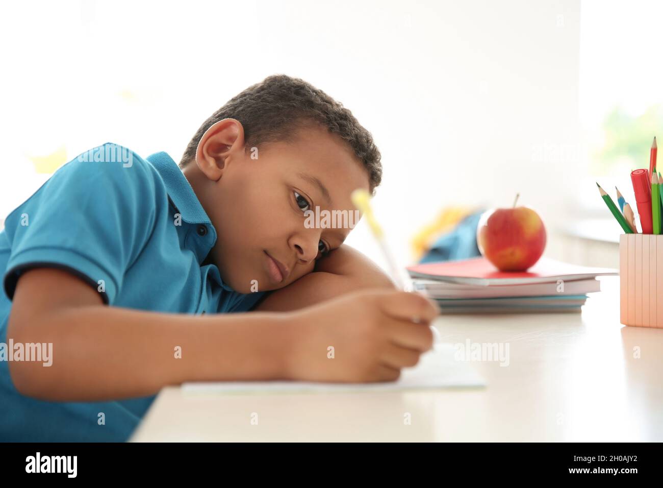 Cute little child doing assignment at desk in classroom. Elementary ...