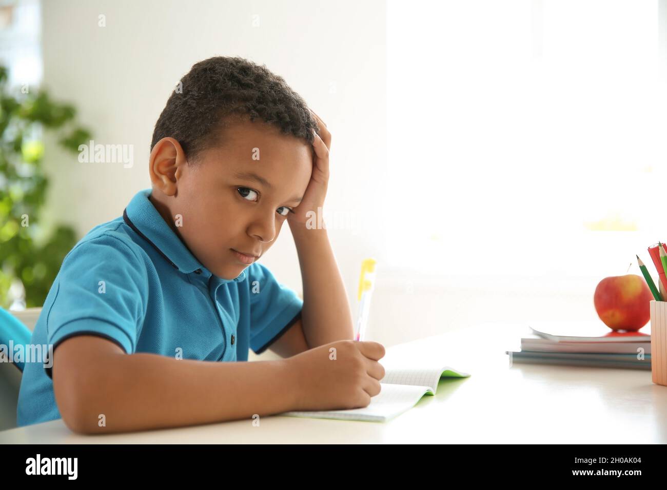 Cute little child doing assignment at desk in classroom. Elementary ...