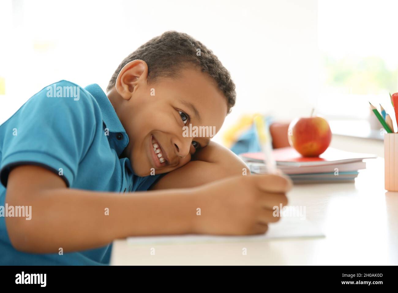 Cute little child doing assignment at desk in classroom. Elementary ...