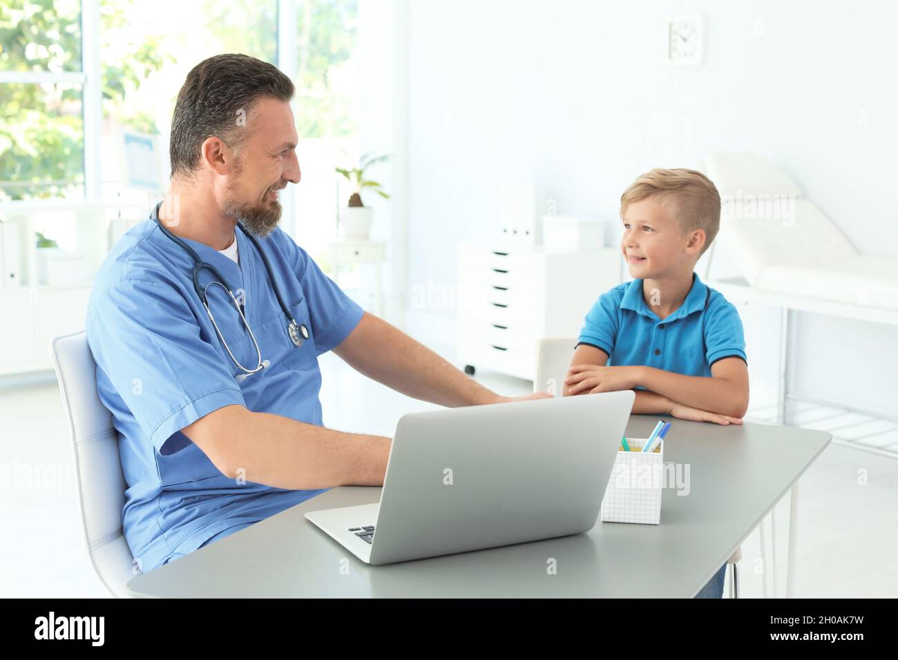 Male medical assistant consulting child in clinic Stock Photo - Alamy