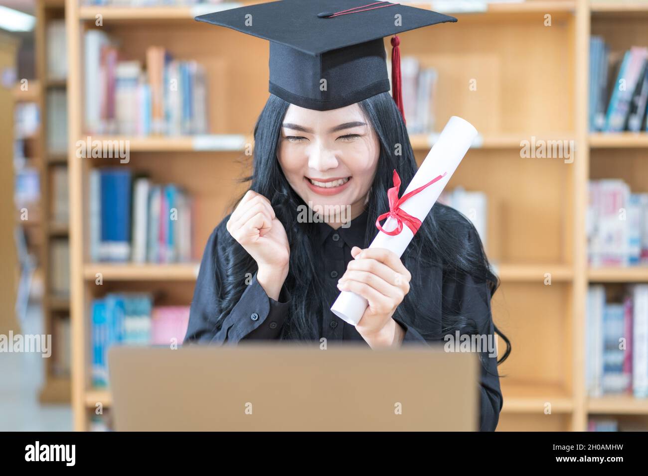 Southeast-Asian university female graduate in graduation gown with ...