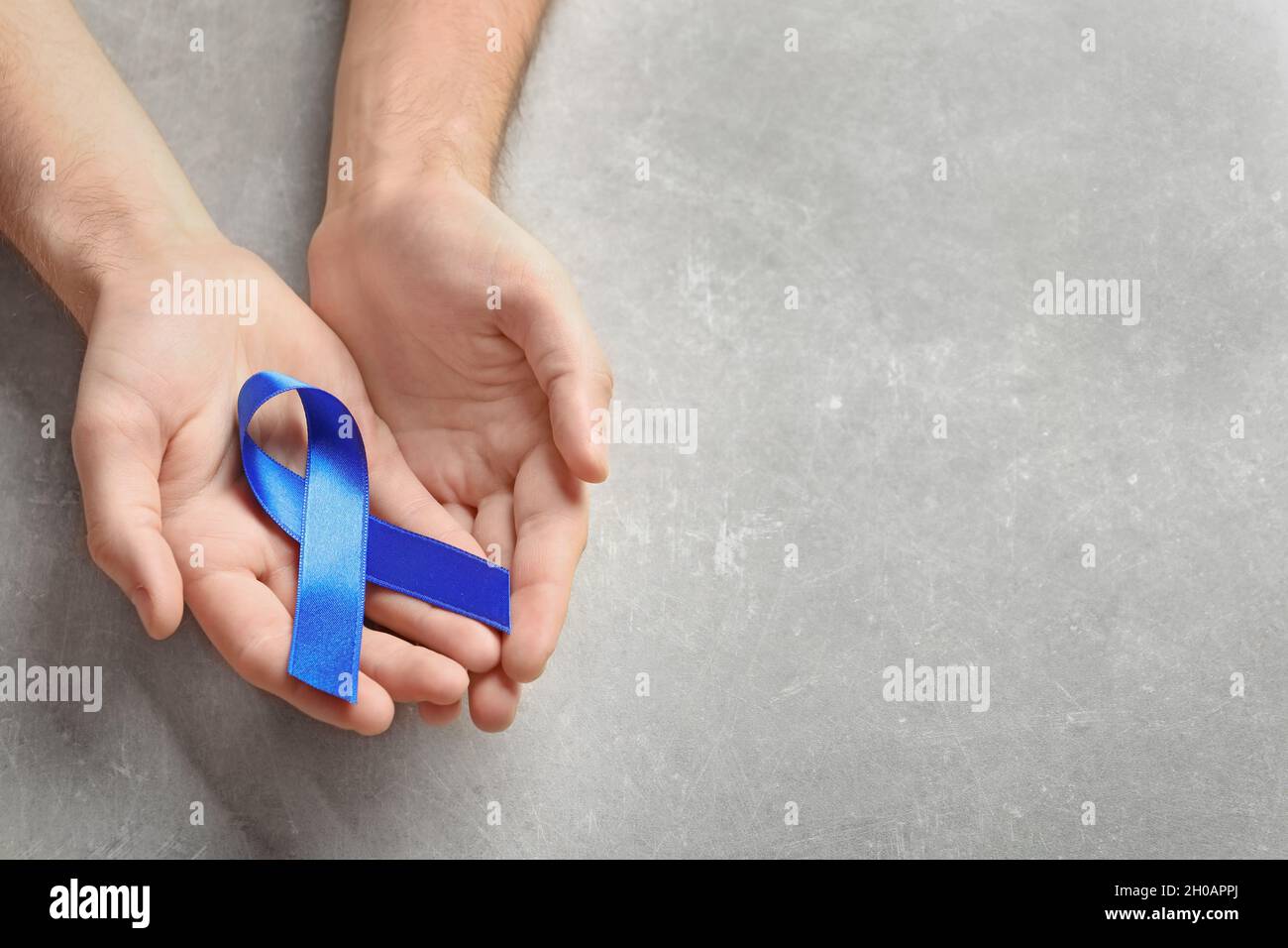 Man holding blue ribbon on grey background. Cancer awareness Stock ...
