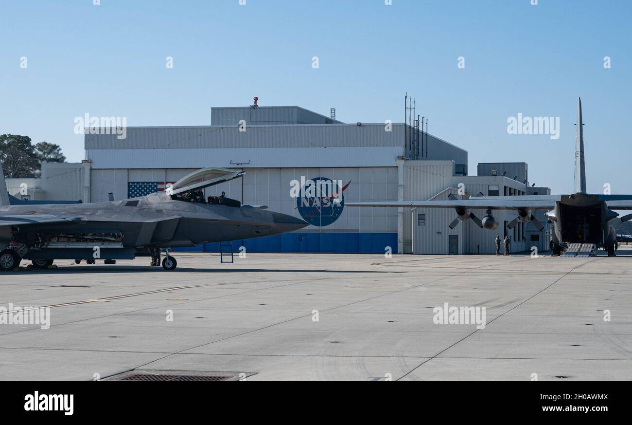 A U.S. Air Force F-22 Raptor and a C-130 Hercules sit on an airfield ...