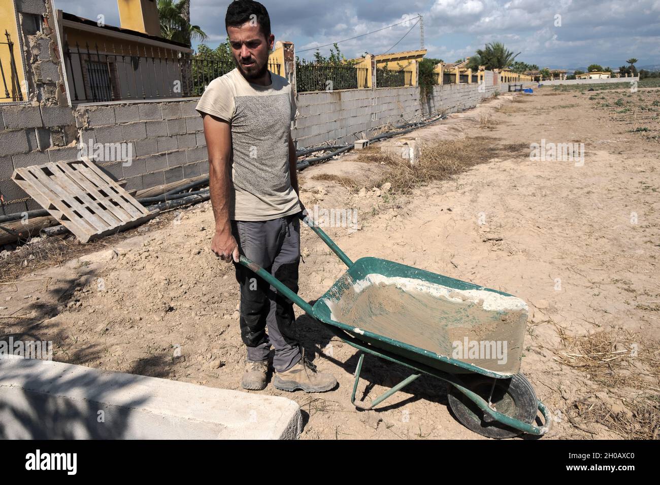 Young worker transporting materials with a wheelbarrow. Effort concept ...