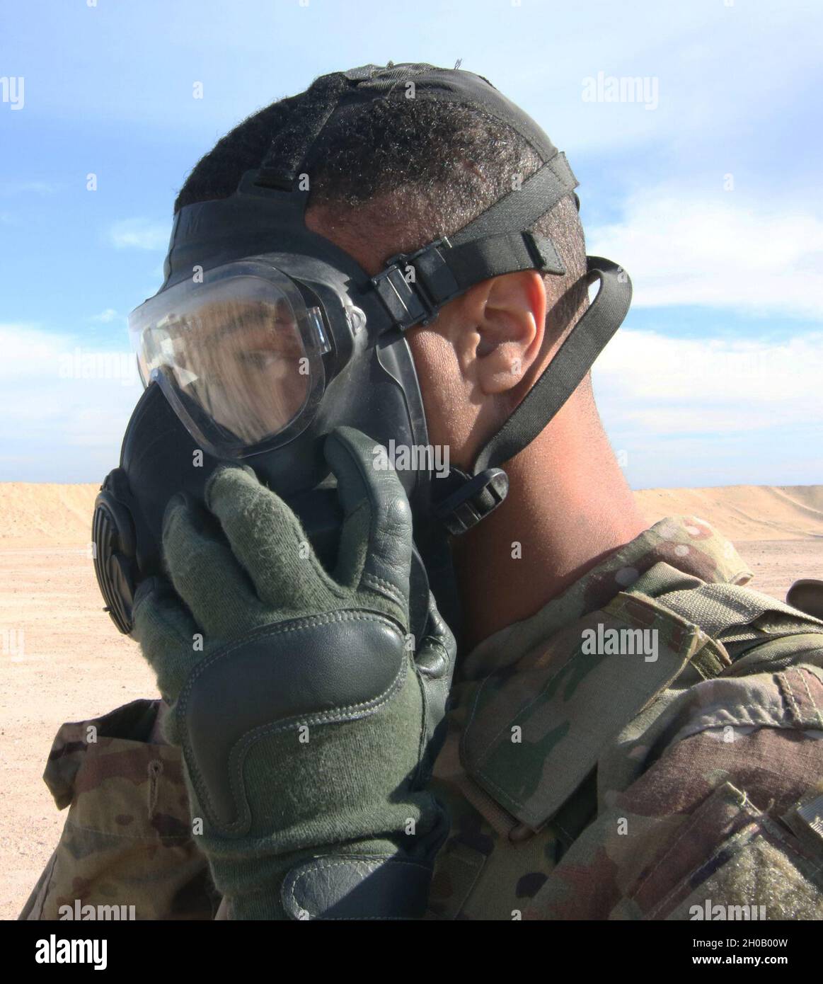 A Soldier with the 40th Brigade Engineer Battalion dons his gas mask to ...