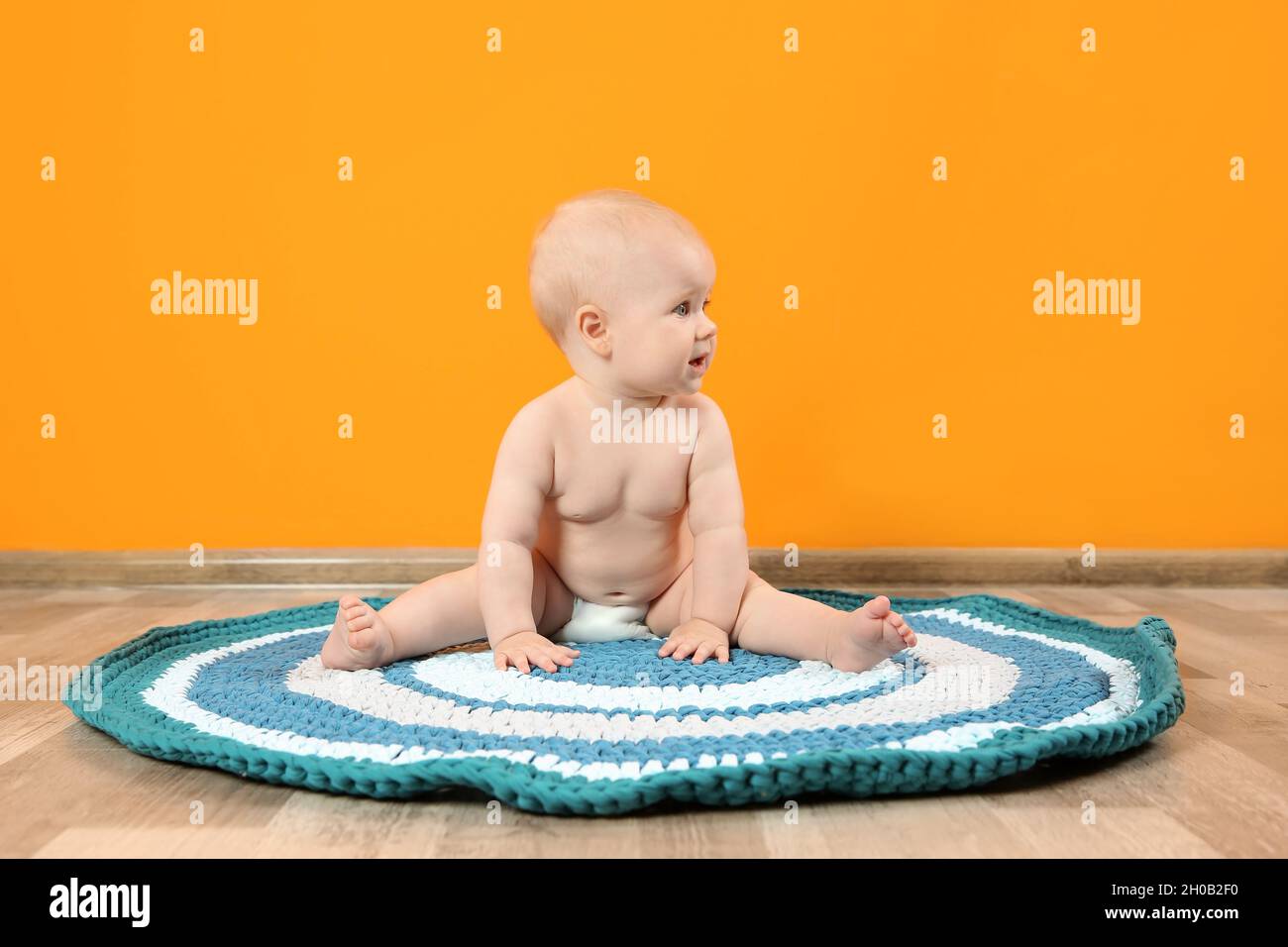 Cute little baby on soft rug near color wall Stock Photo - Alamy