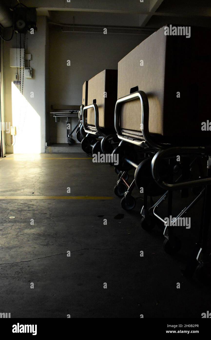 Wheeled gurneys with empty cardboard boxes are staged at the rear ...