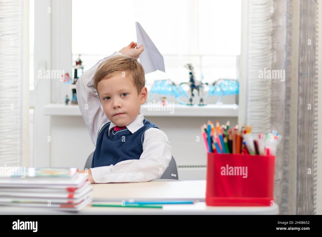 A cute first-grader boy in a school uniform at home while isolated at ...