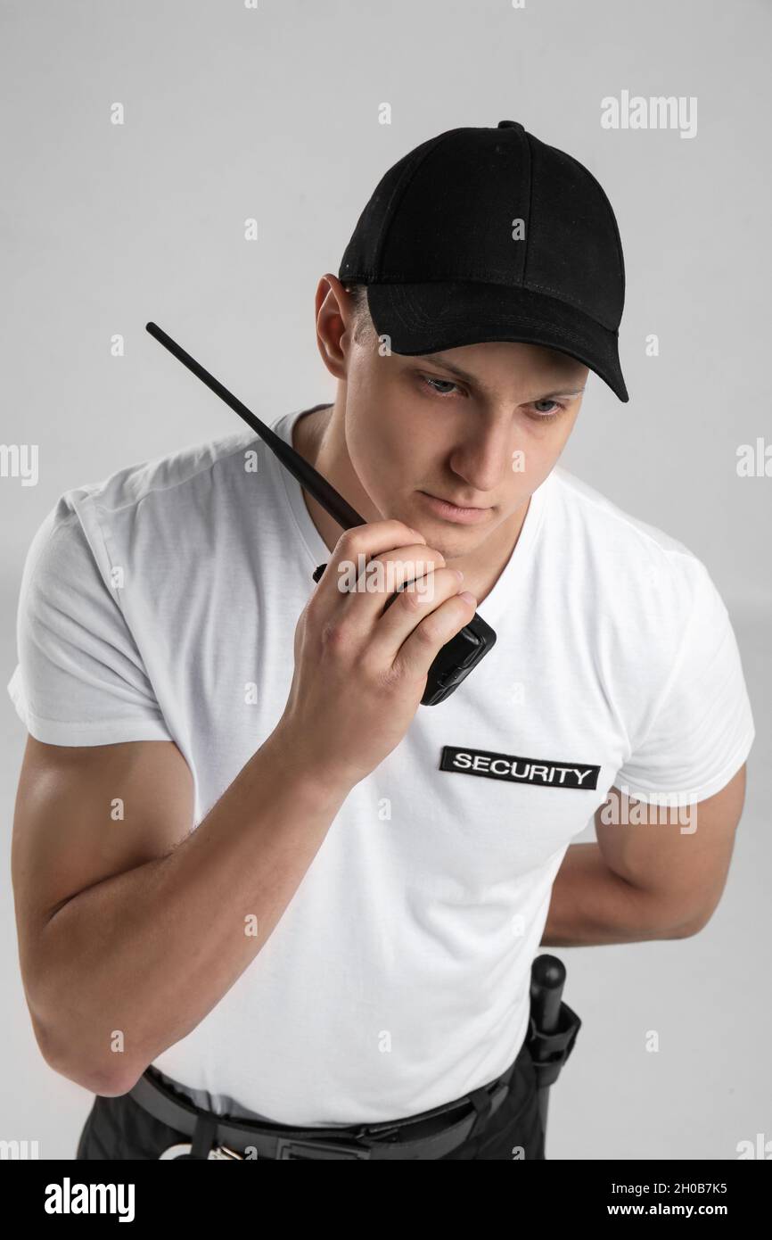 Male security guard using portable radio transmitter on color ...