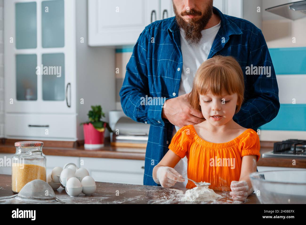 Little beautiful girl cooking food with father in kitchen interior ...