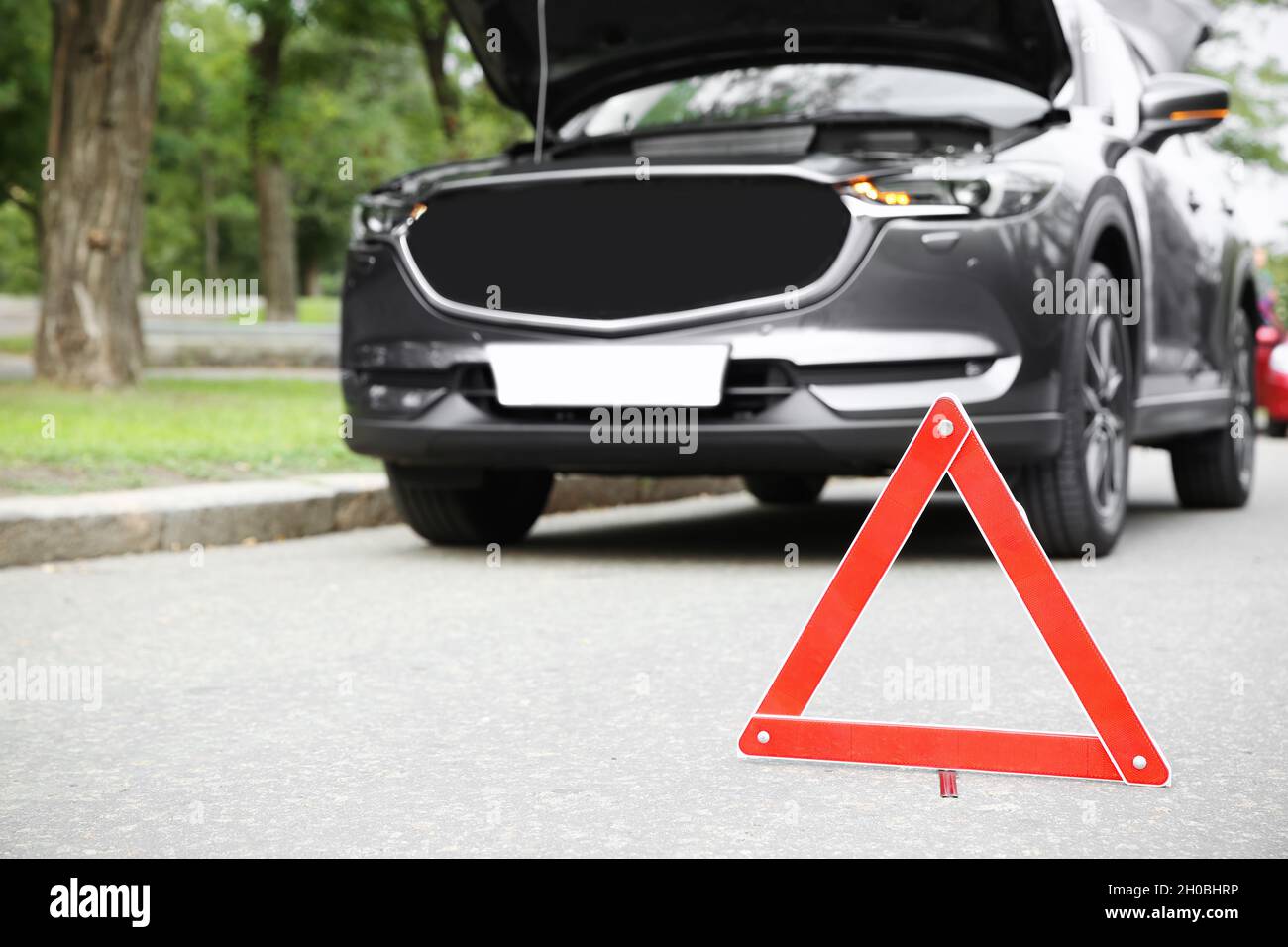 Emergency stop sign near broken car on road Stock Photo - Alamy