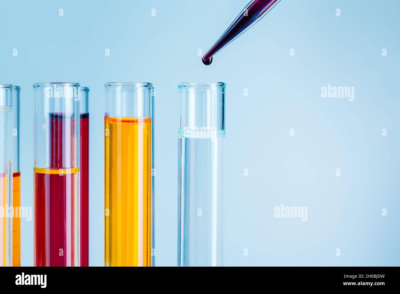 Laboratory test tubes with red and yellow liquids on light blue ...