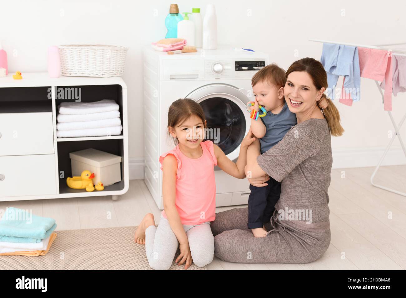 Housewife with little children in laundry room Stock Photo - Alamy