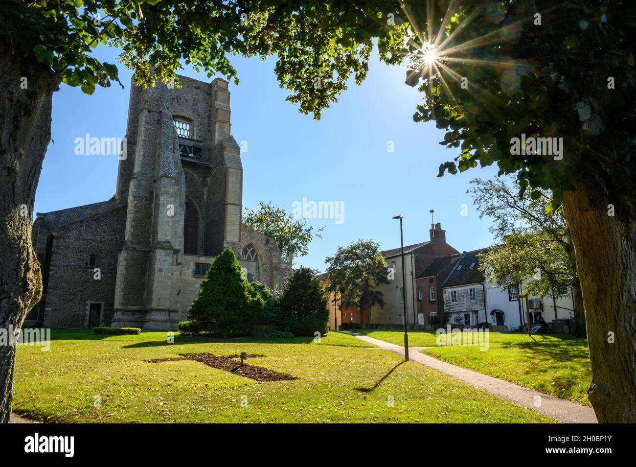 The sun shines brightly through the leaves of trees in front of St ...