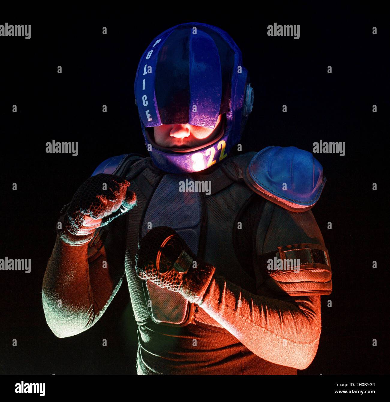 Male robot cop waves and punches his fits in dark. Halfman is ready for ...