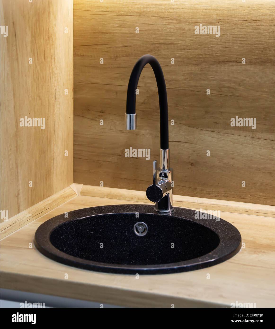 Modern faucet in the kitchen and washbasin in black. Wood table top ...