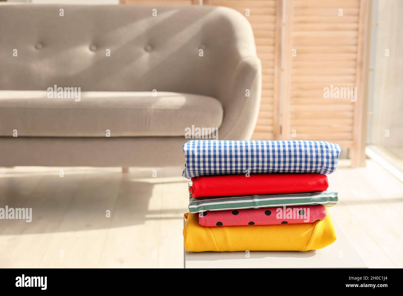 Stack of clothes on table in living room Stock Photo - Alamy