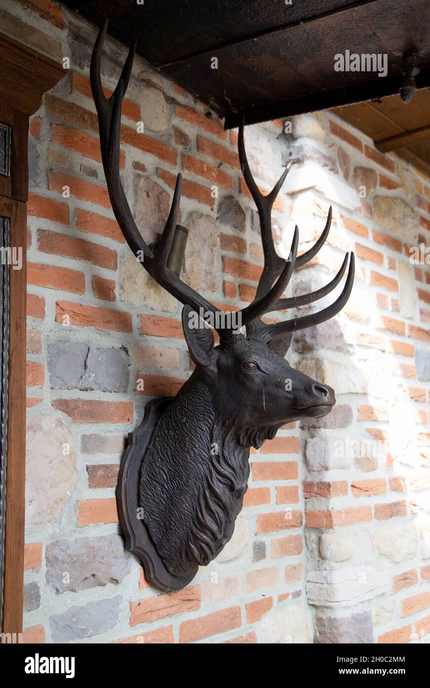 Bronze deer mannequin hanging on a brick wall Stock Photo - Alamy