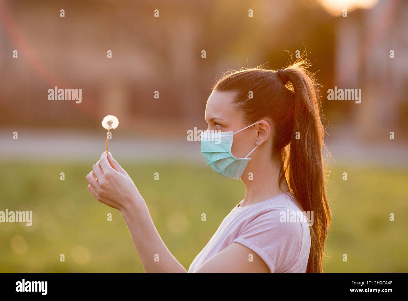 Afraid woman with mask looking at dandelion and having panic reaction ...