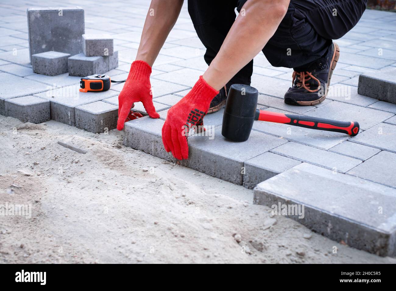 The master in yellow gloves lays paving stones in layers. Garden brick ...