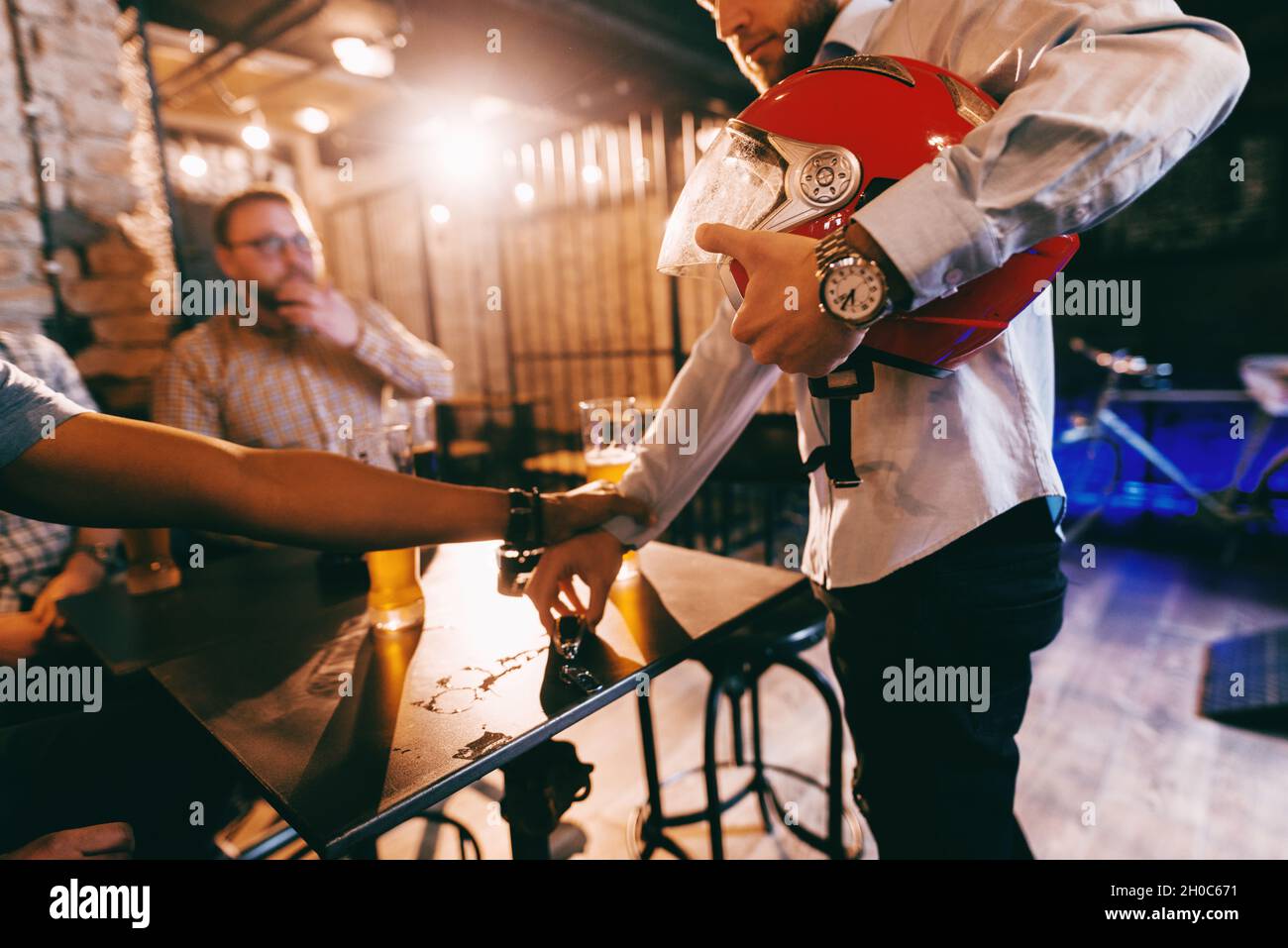 Drunk man attending to drive and his friend stopping him. Pub interior ...