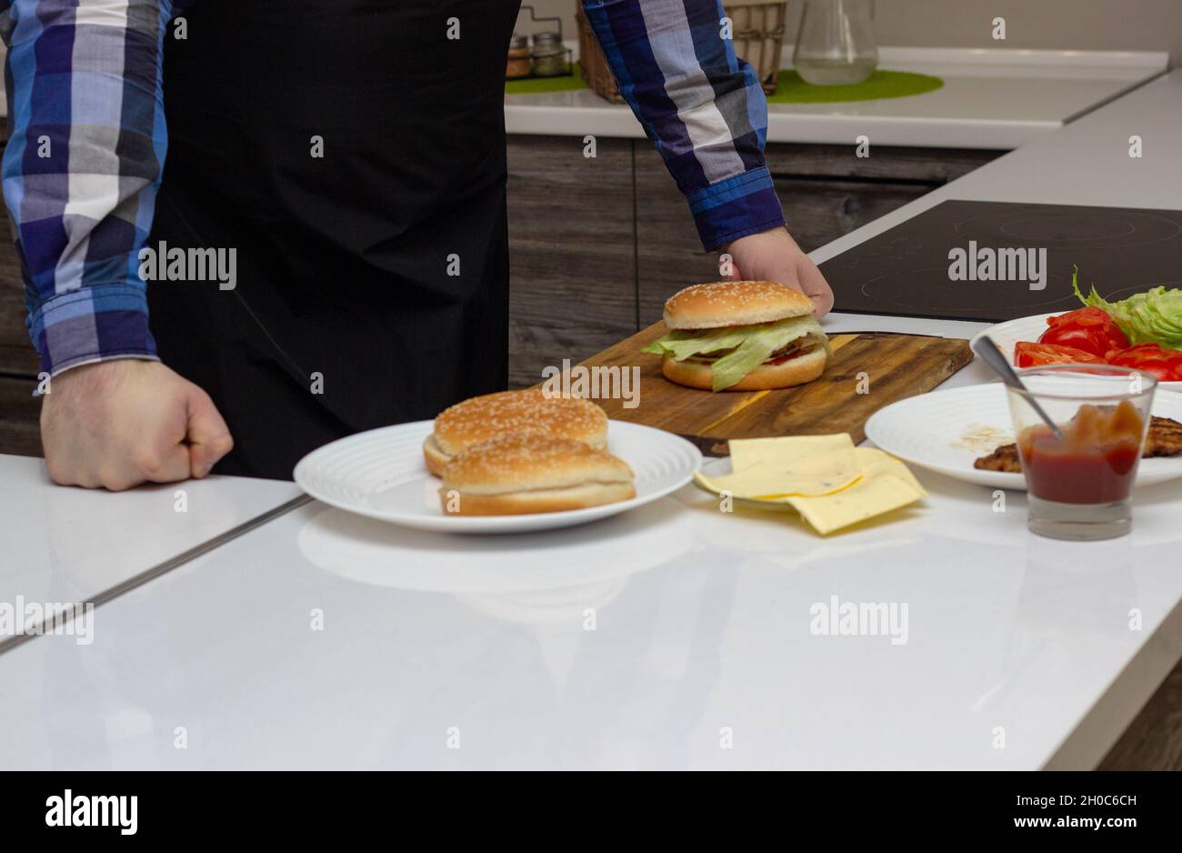 Man in black apron prepares homemade burgers with ingredients, copy ...