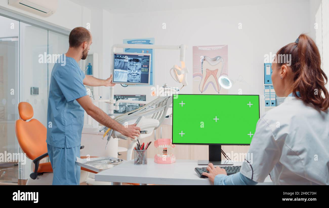 Woman working as dentist with green screen on monitor at dental cabinet ...
