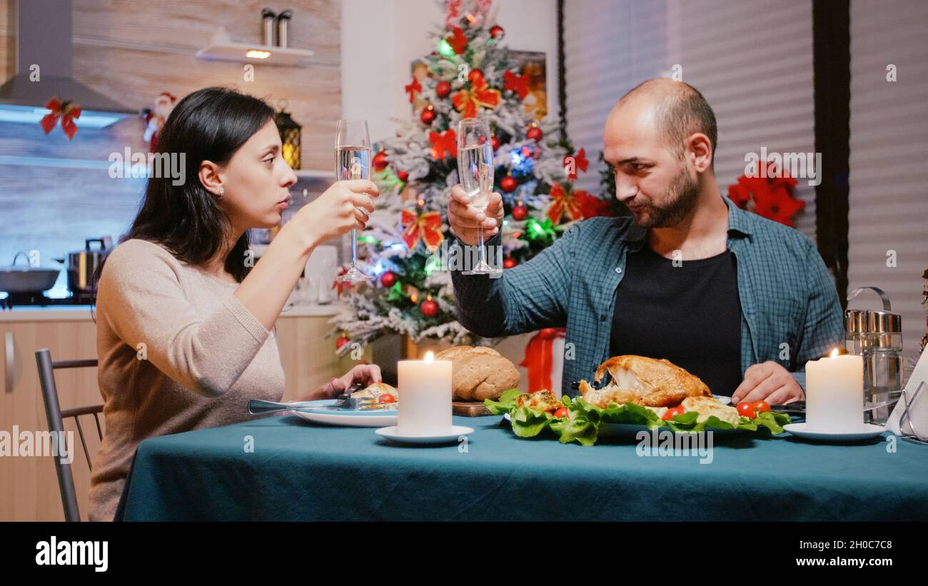Couple clinking glasses of champagne at christmas dinner. Festive man ...