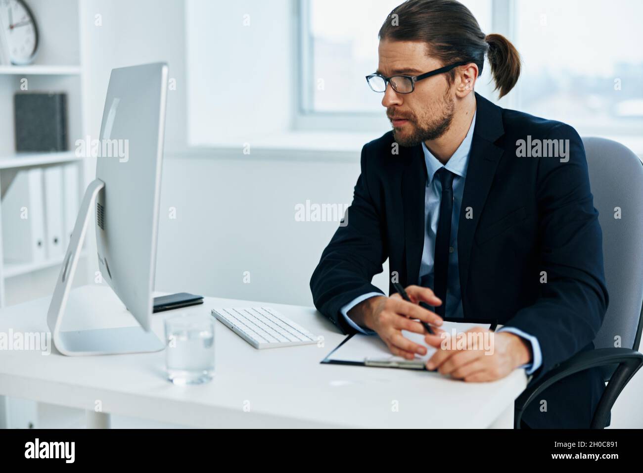office worker sitting at a desk in front of a computer Lifestyle Stock ...