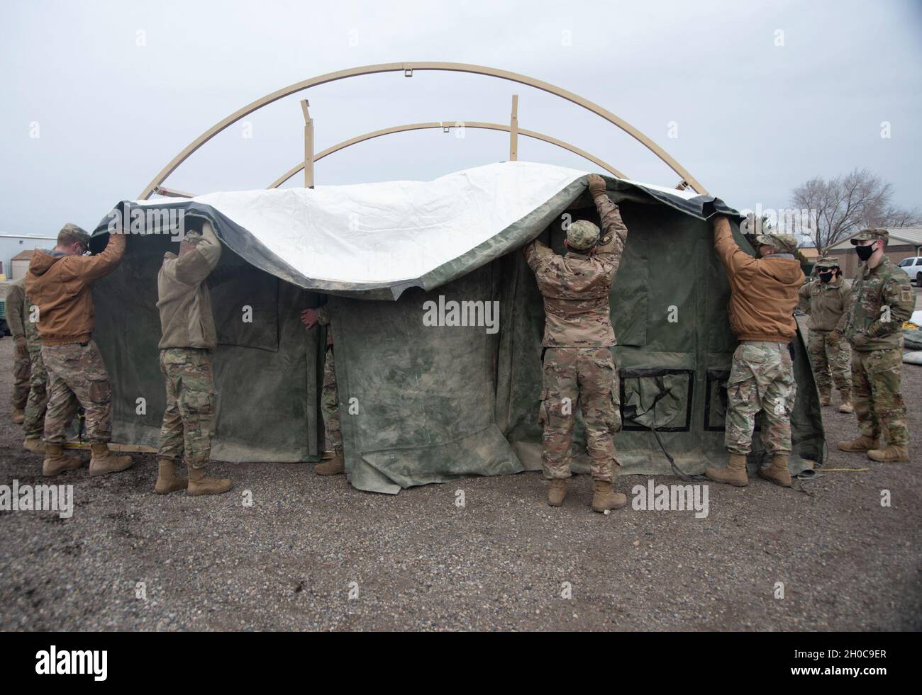 A group of U.S. Air Force Airmen lift a door frame of a small shelter ...