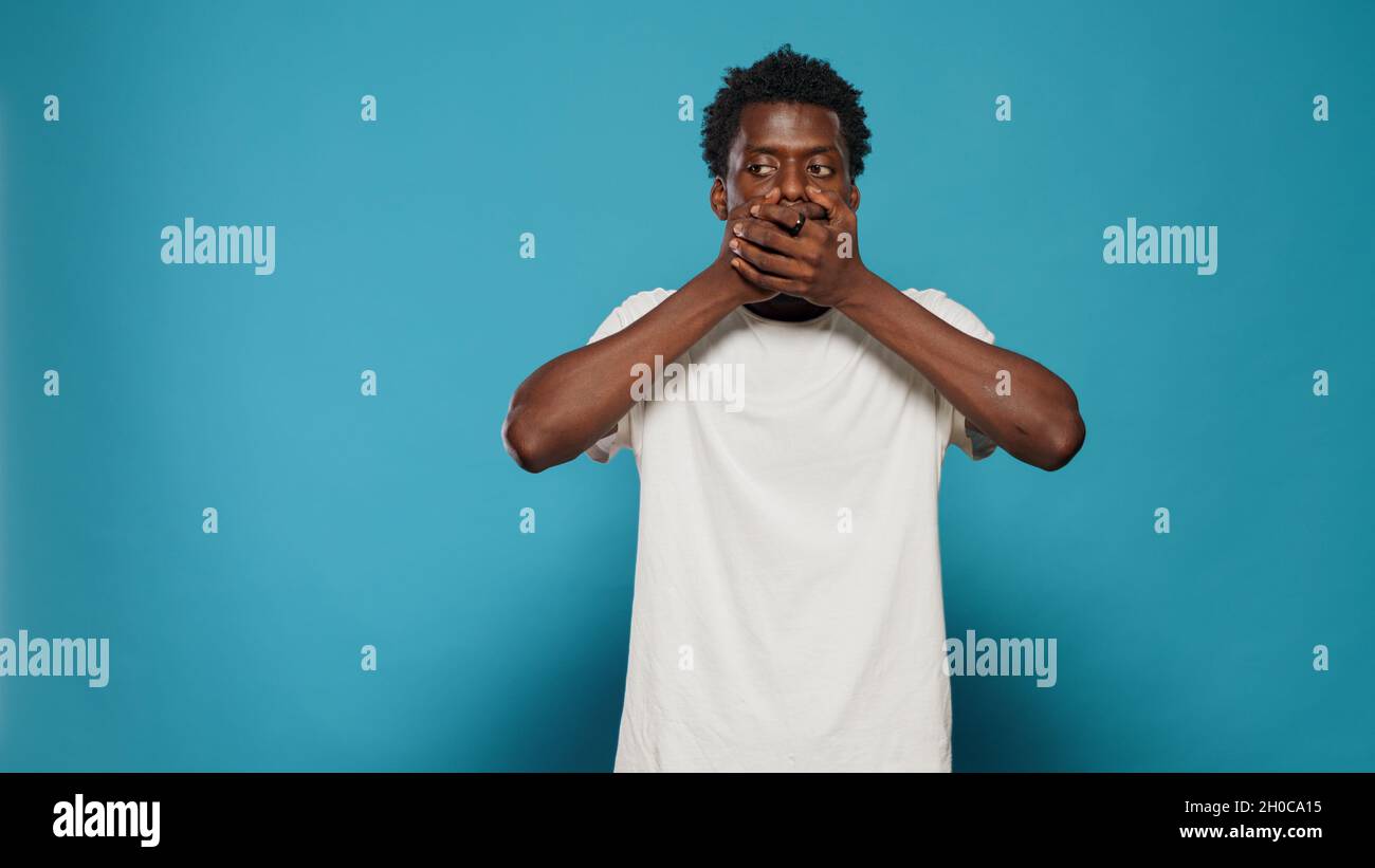 Man covering mouth after spilling secret by accident in studio. Young ...