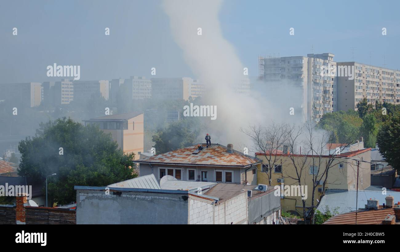 Firefighters on roof of burning house trying to extinguish flames. Team ...