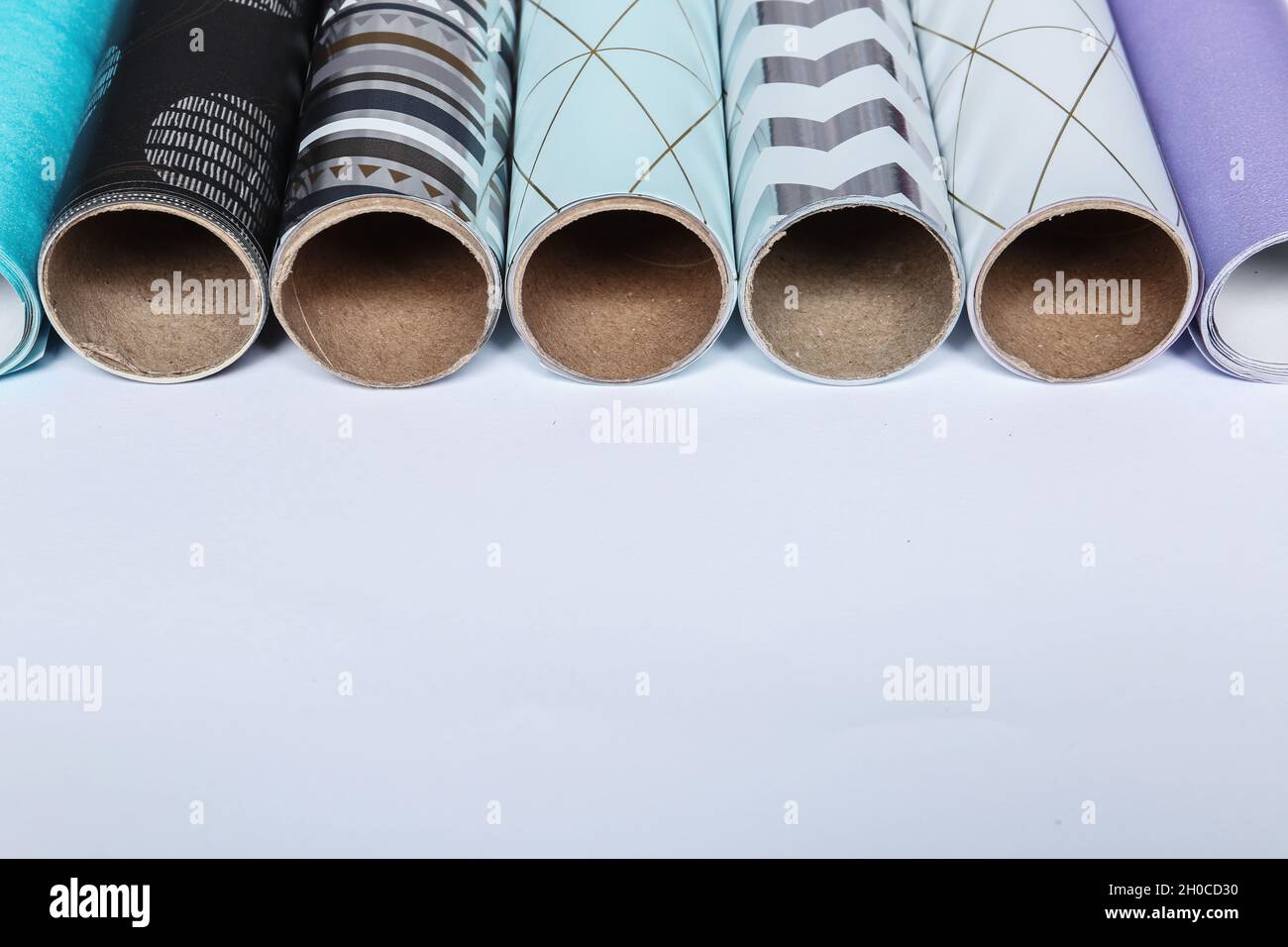 Rolls of festive wrapping paper and space for text on white background ...