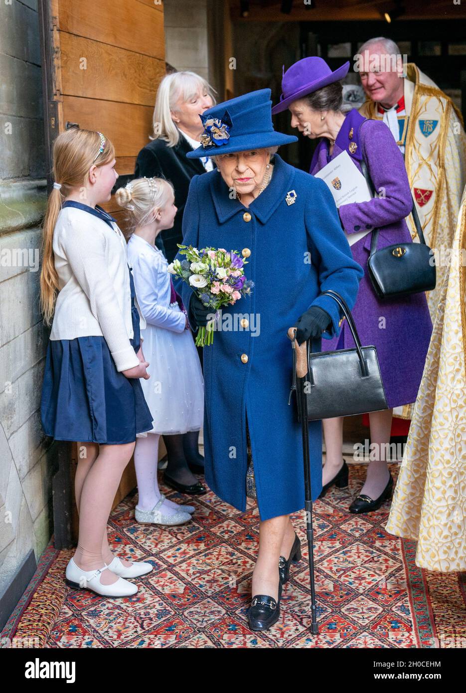 Queen Elizabeth II uses a walking stick as she arrives with the ...