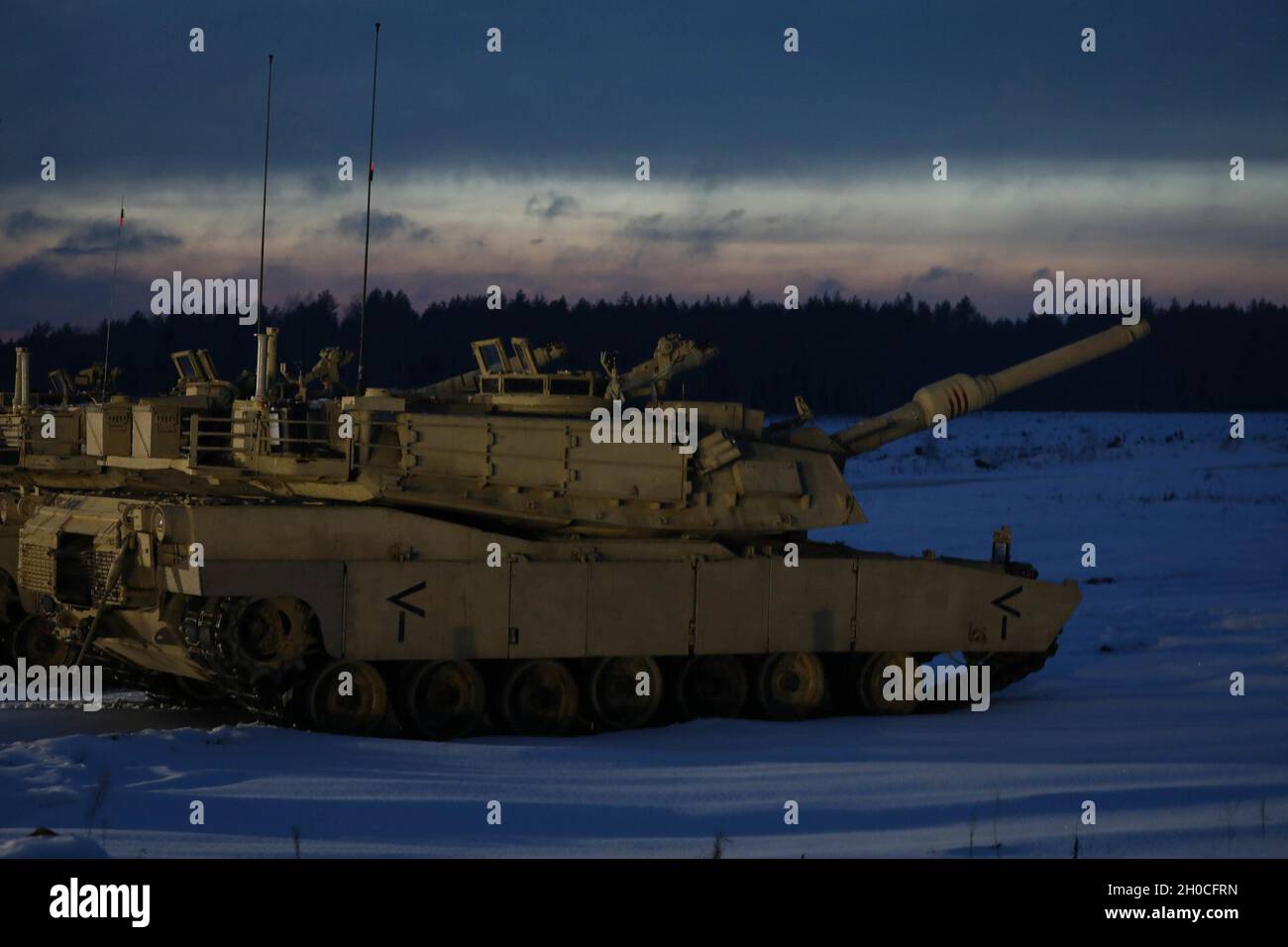 Abrams Tanks are parked in a line on a range before a nighttime section ...
