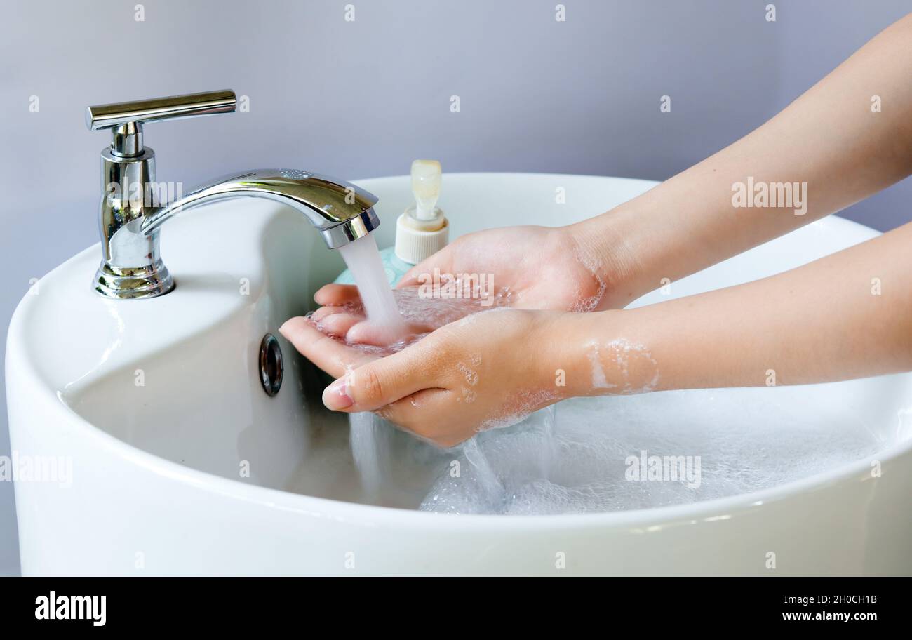 Washing hands in a round white ceramic basin, soap bubbles on hand ...