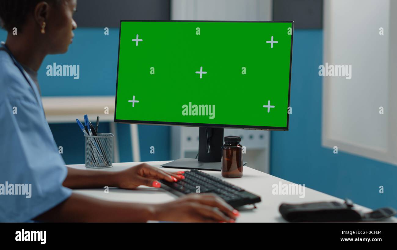 Close up of medical specialist using green screen on monitor at desk in ...