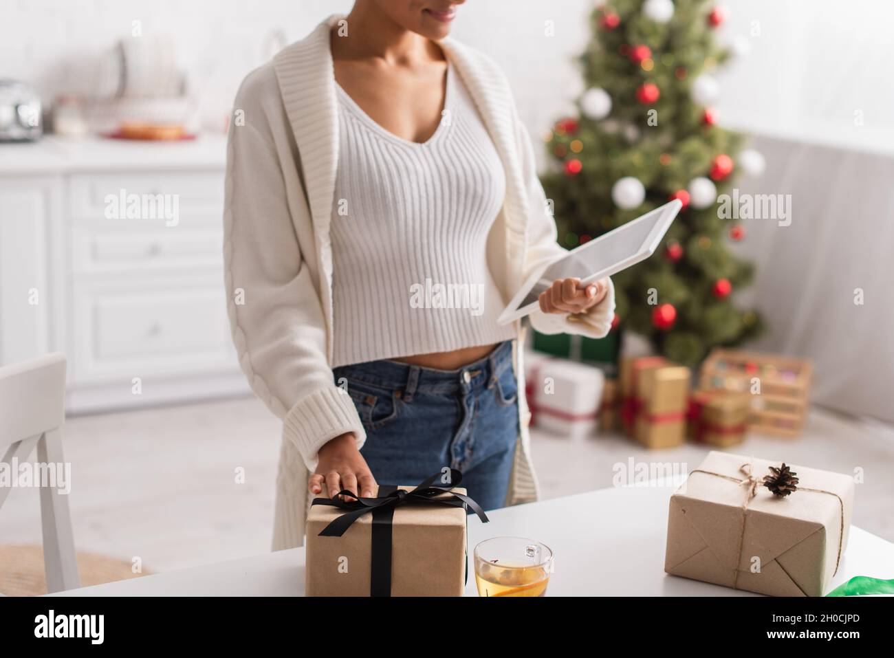 Cropped view of african american woman holding digital tablet near tea ...