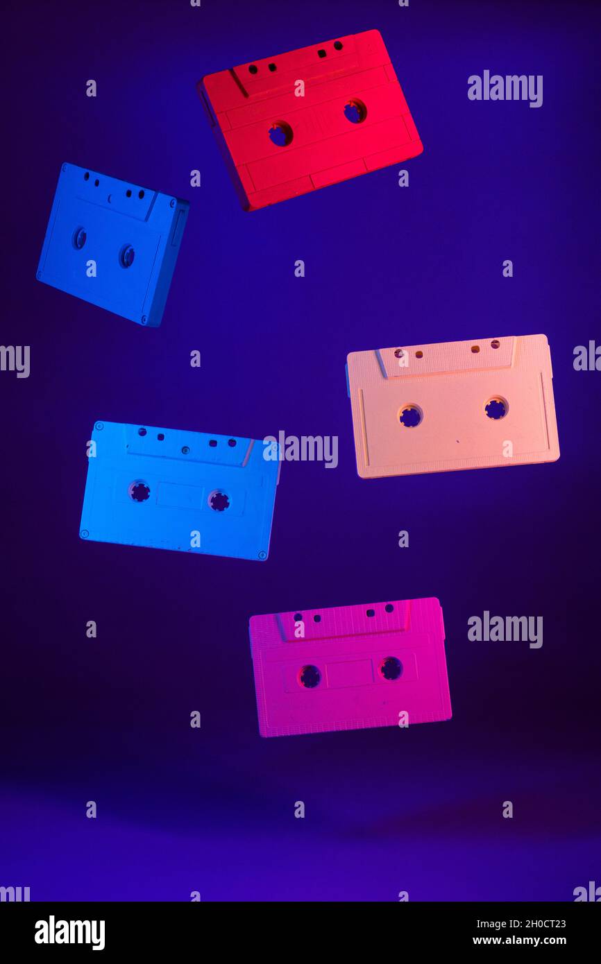 Colored audio cassettes hanging in the air against purple background ...