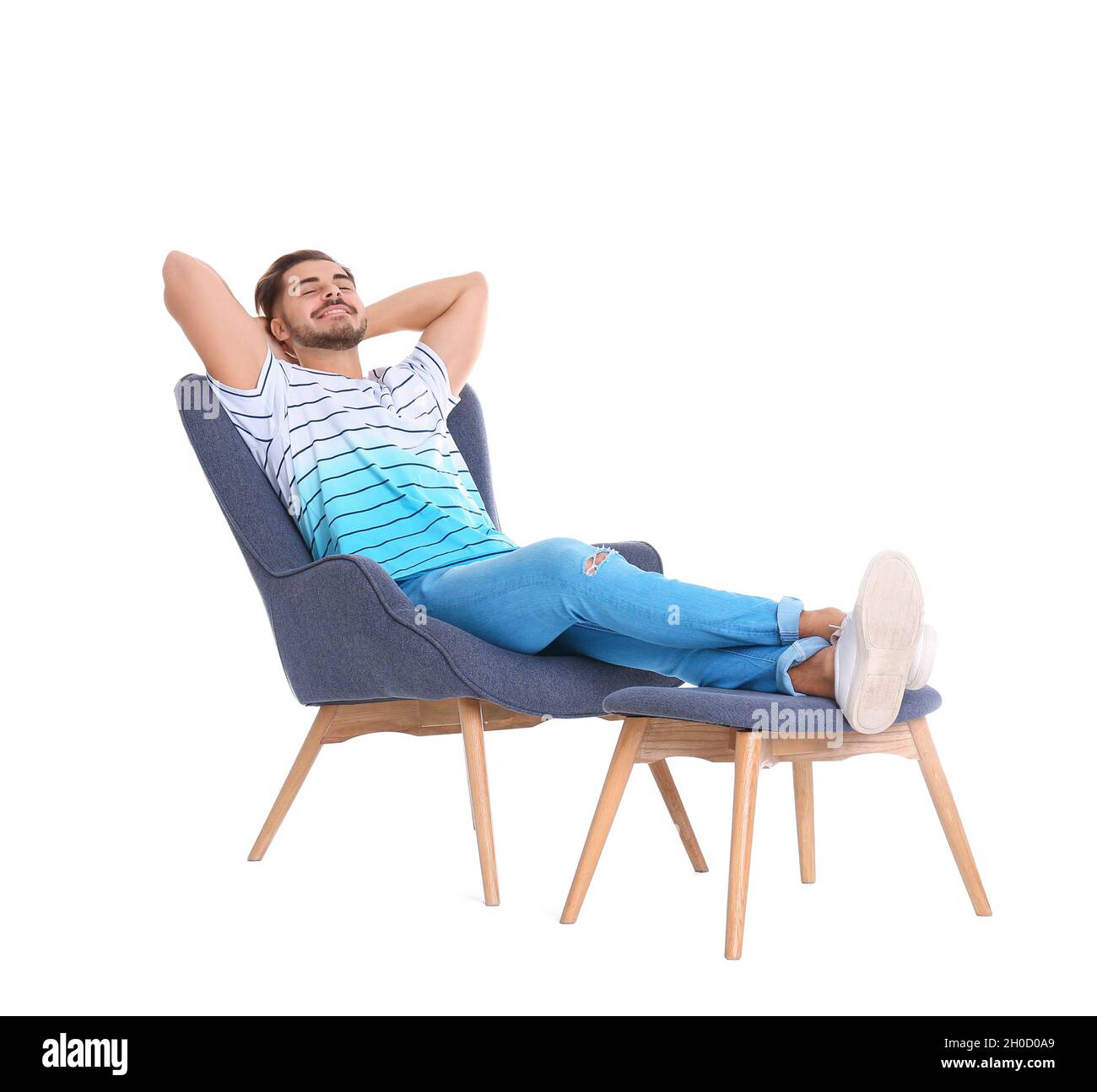 Handsome young man relaxing in armchair with legs on footrest against ...