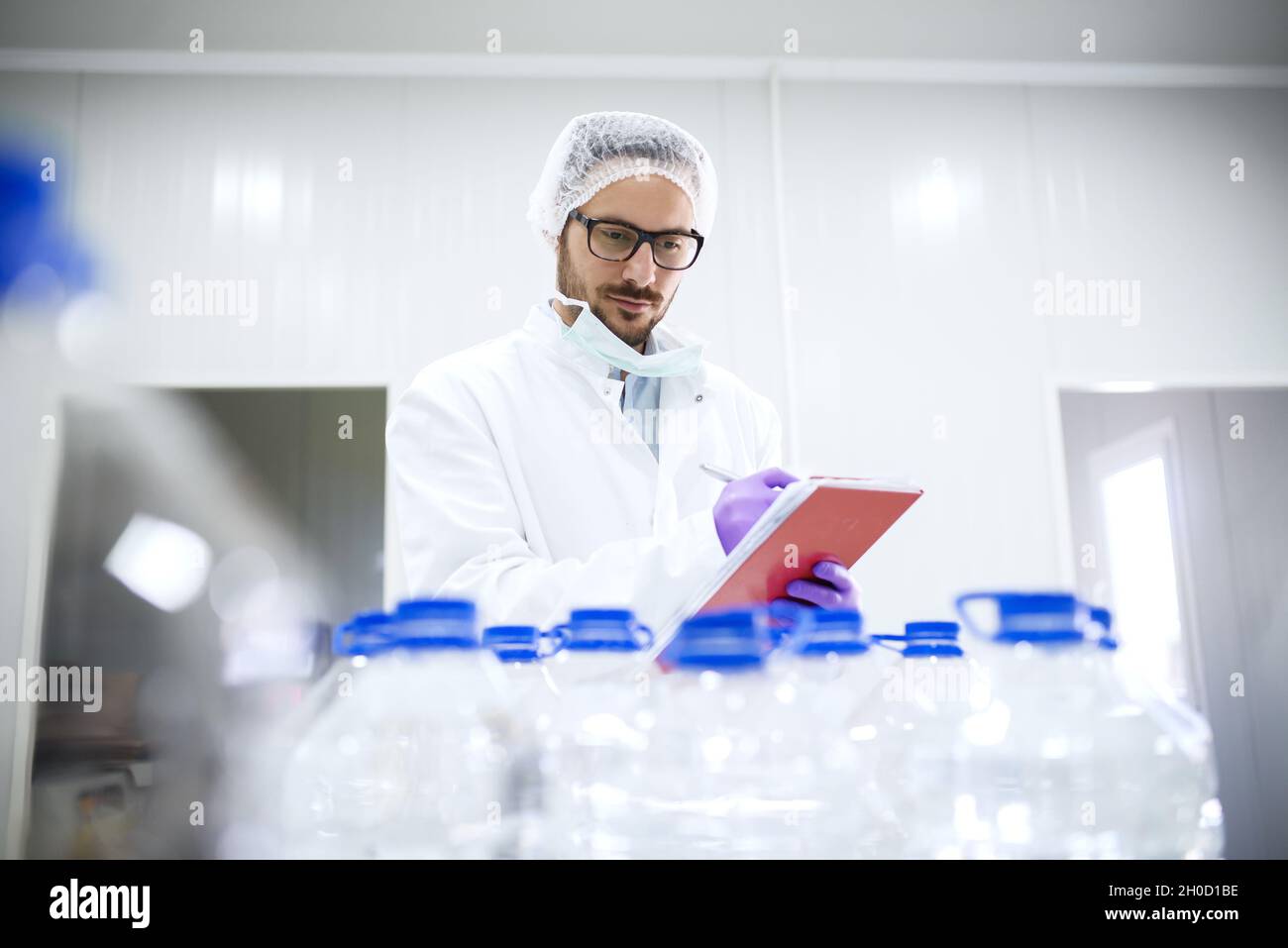 Scientist writing test results while standing in the lab. Protective ...